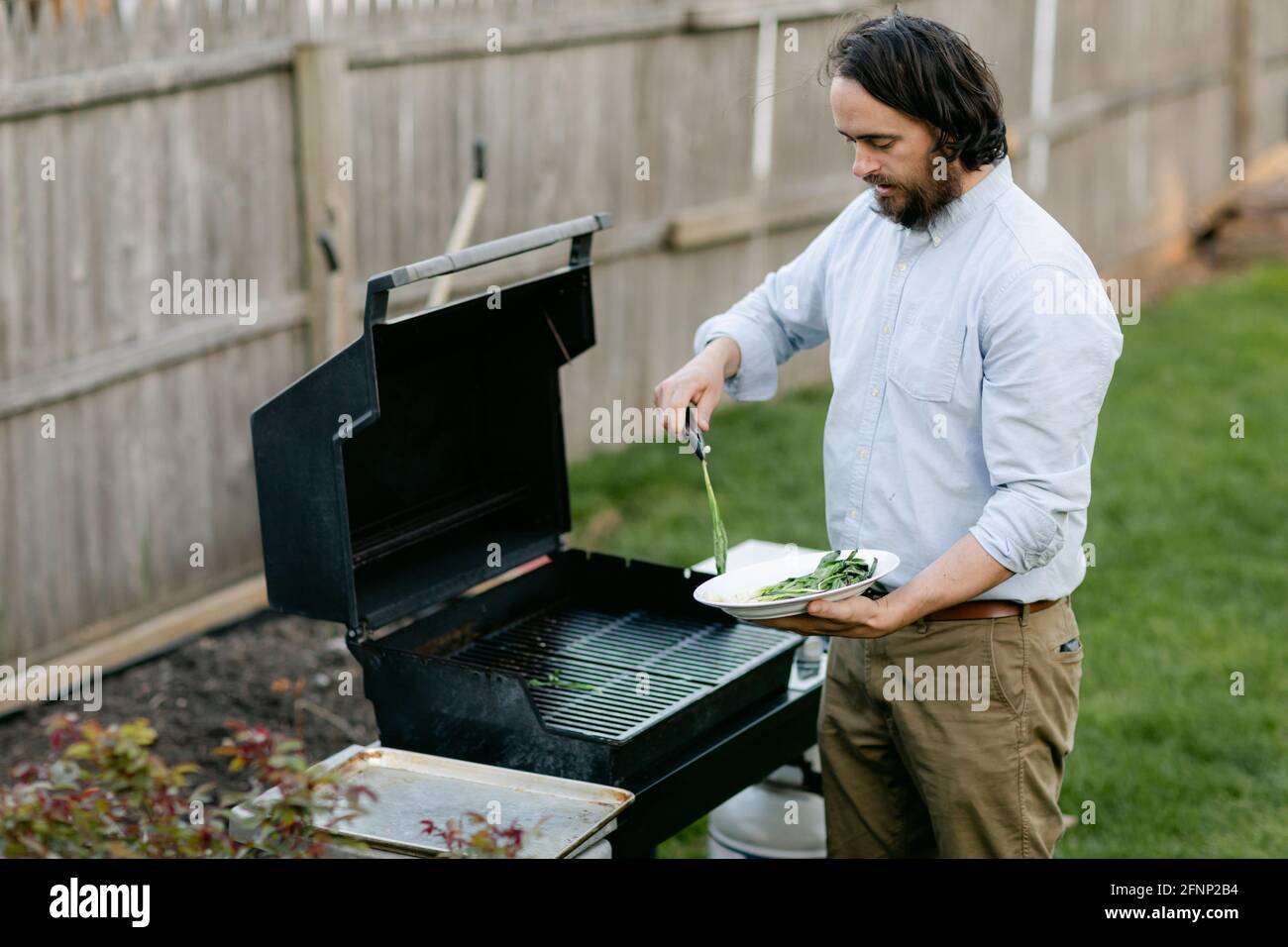 Man in his urban backyard grilling wild ramps Stock Photo - Alamy