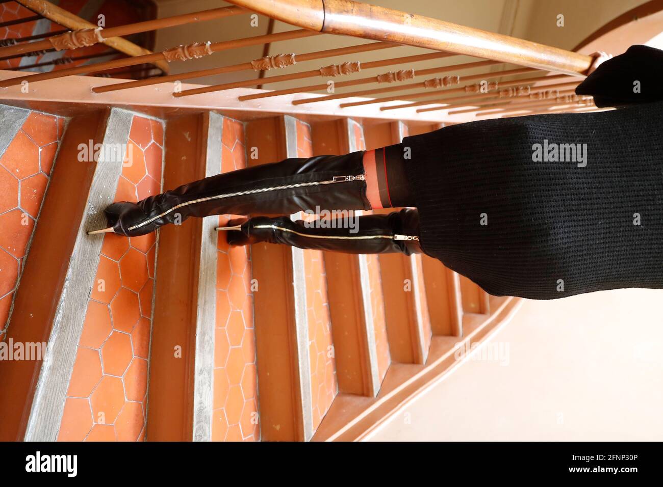 Back view of a woman in high heel boots walking up wooden stairs ...