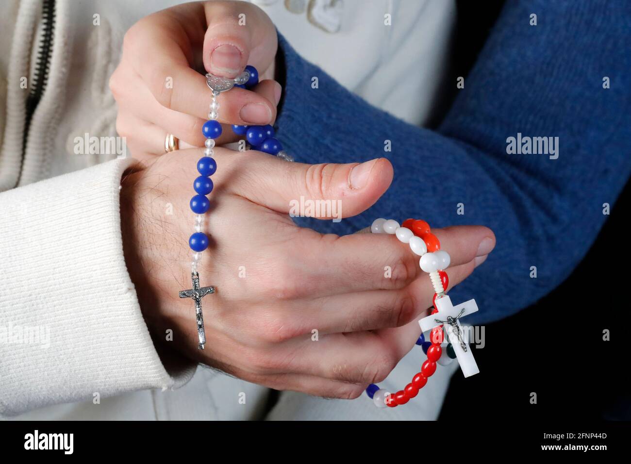 Catholic man and woman praying together at home. Close up on hands with ...