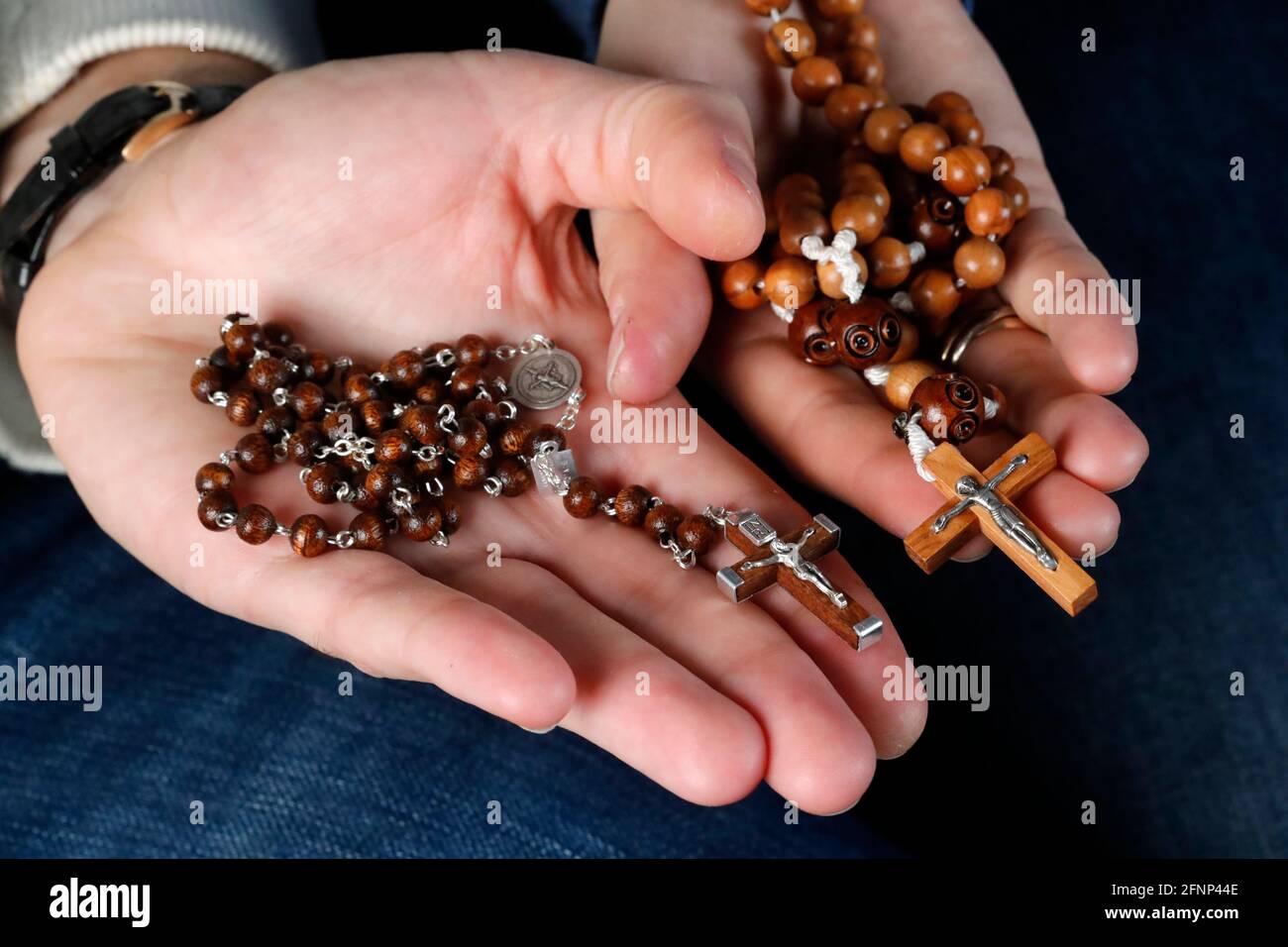 Catholic man and woman praying together at home. Close up on hands with ...