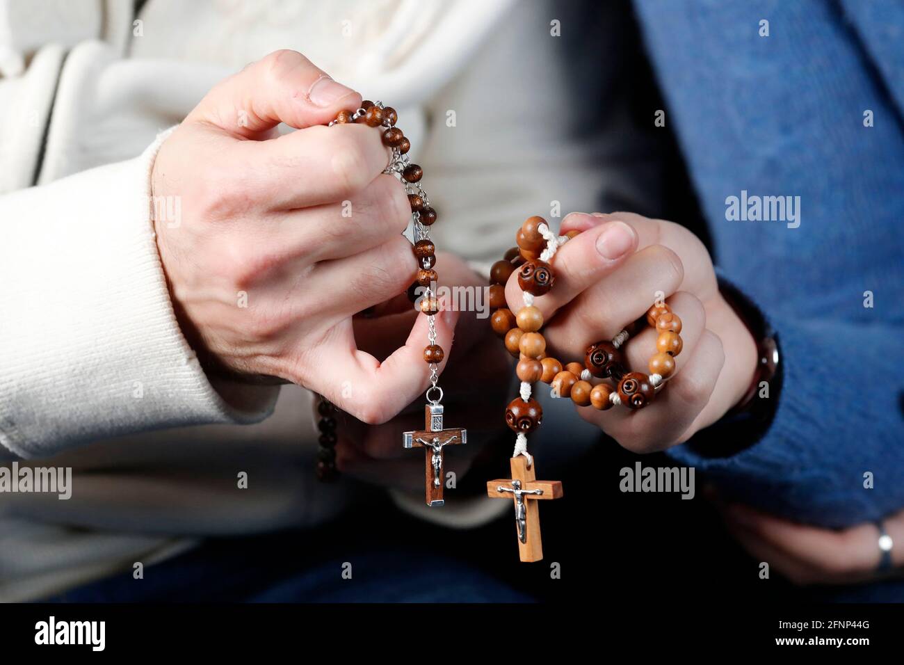 Catholic man and woman praying together at home. Close up on hands with ...