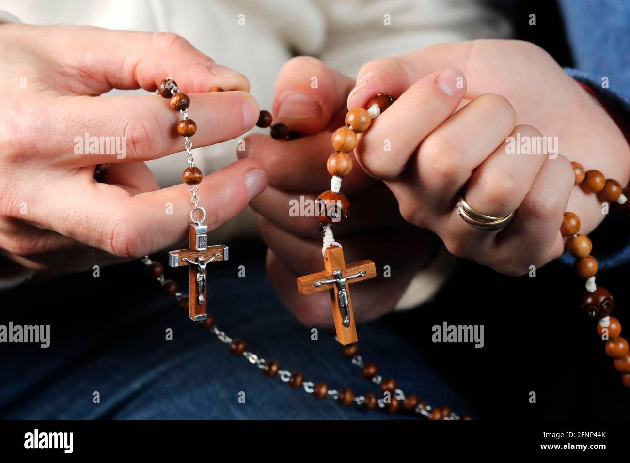 Catholic man and woman praying together at home. Close up on hands with ...