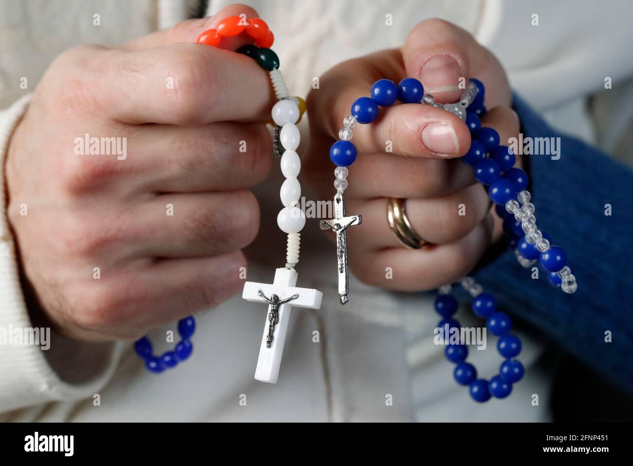 Catholic man and woman praying together at home. Close up on hands with ...