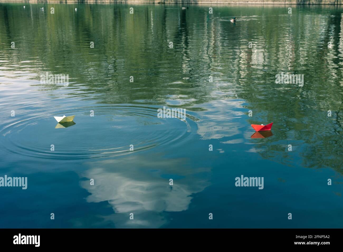 Red and white paper boats float on the water Stock Photo - Alamy