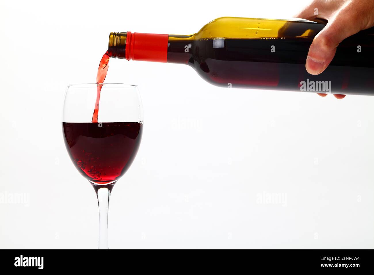 Image of a mans hand pouring red wine from a wine bottle in to a ...