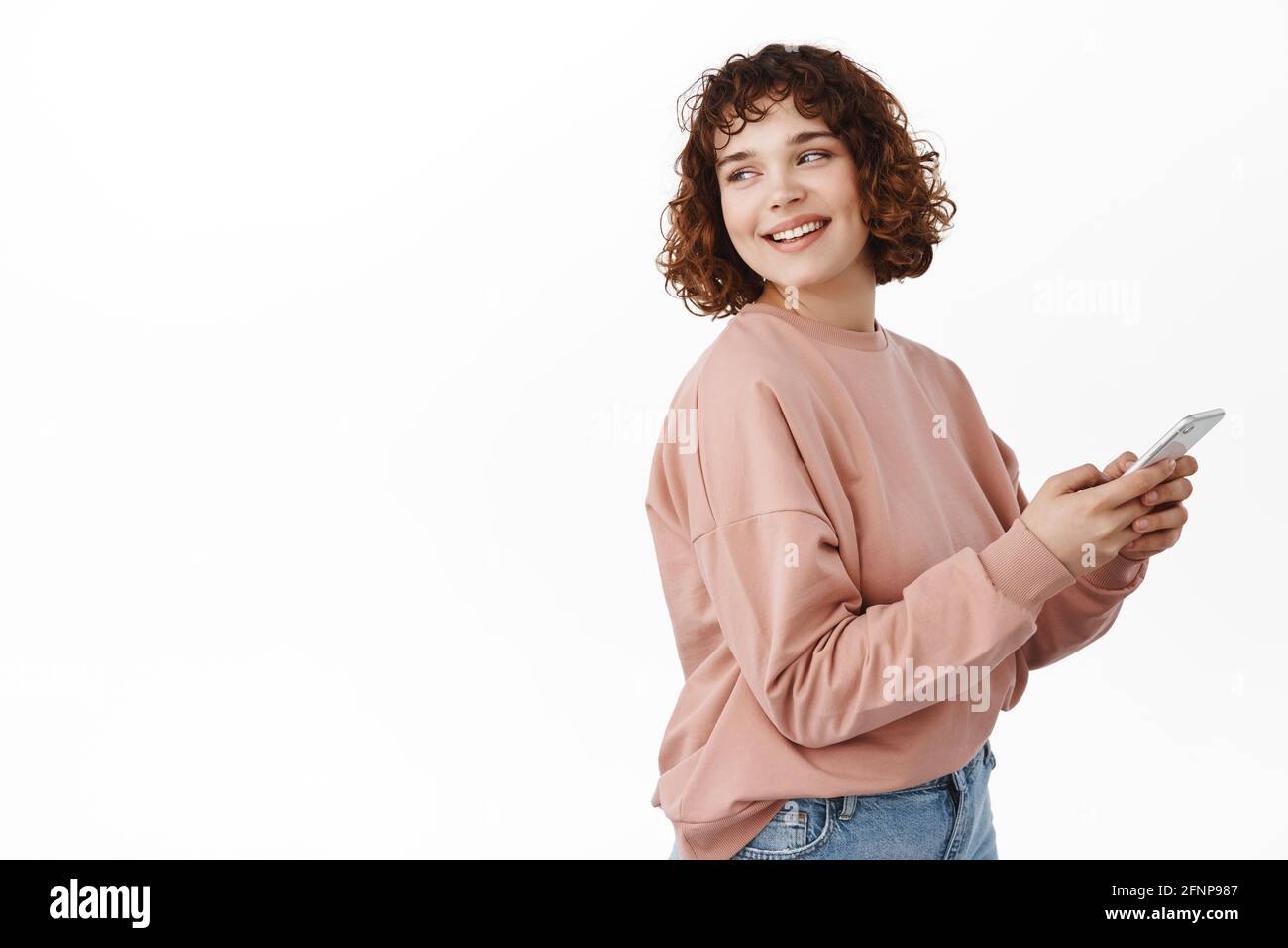 Happy beautiful woman turn back with pleased smile, using chat app ...