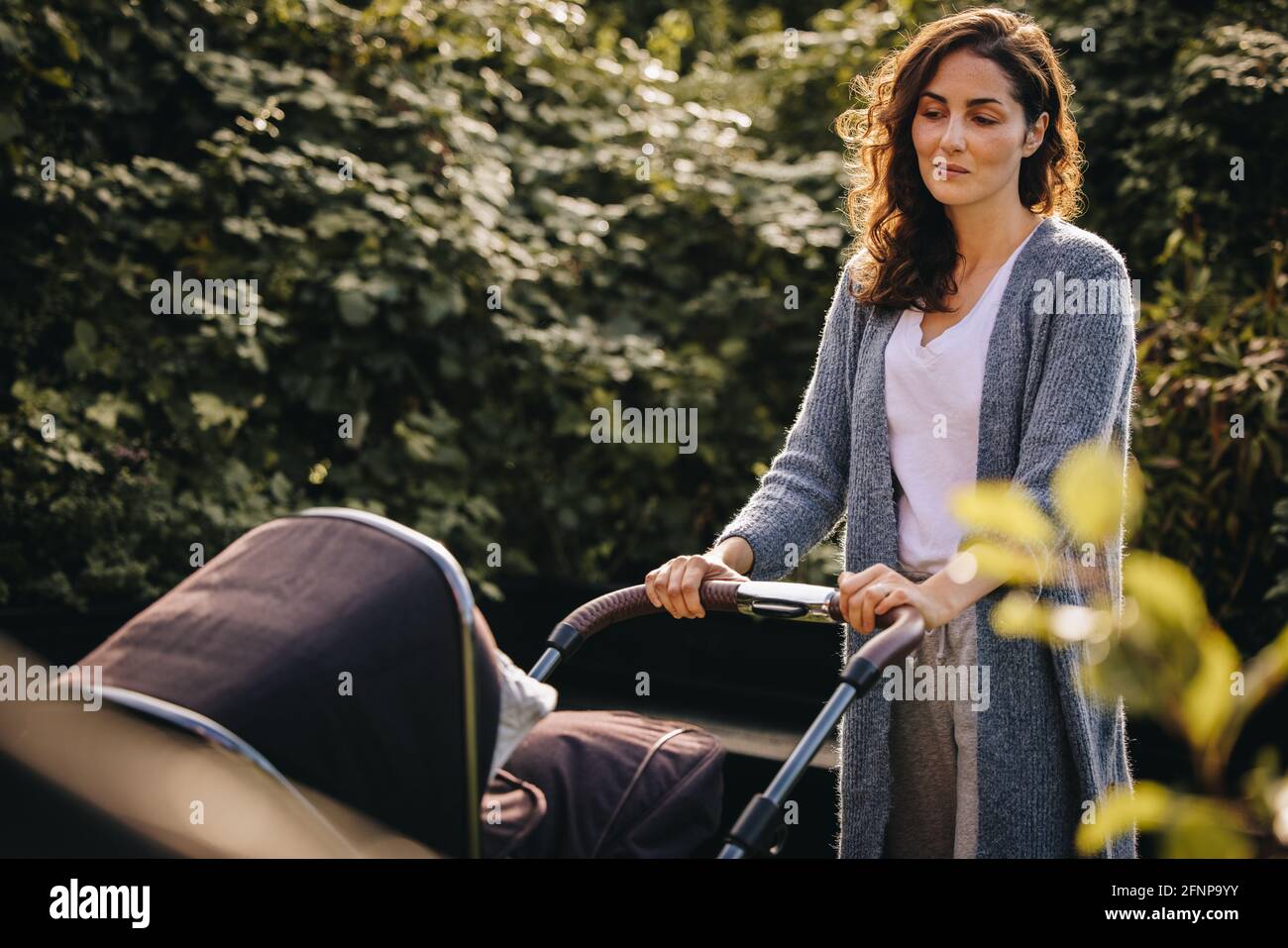 Woman pushing a stroller and looking at her baby. Mother taking her ...