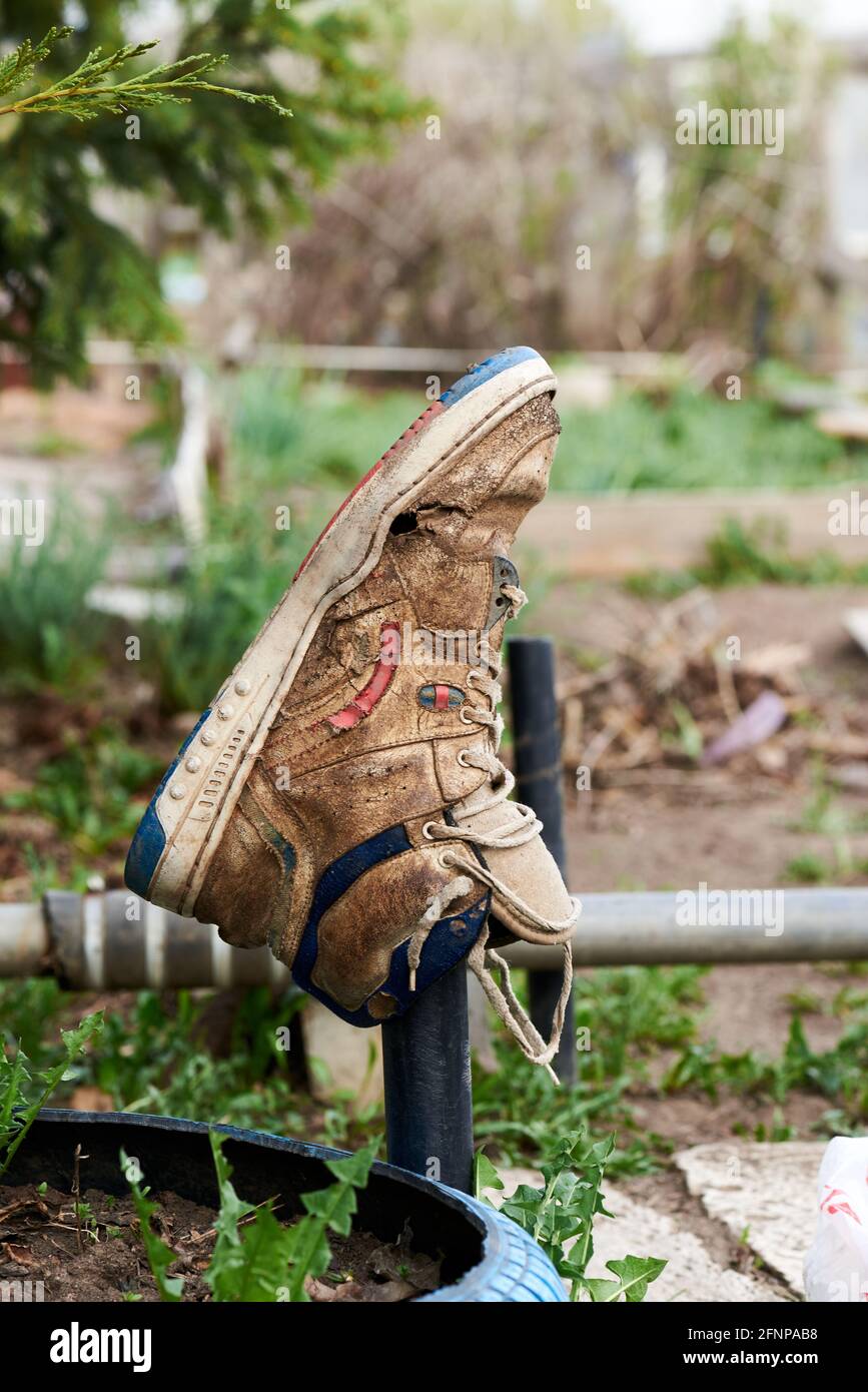old dirty boot hanging on the fence Stock Photo - Alamy