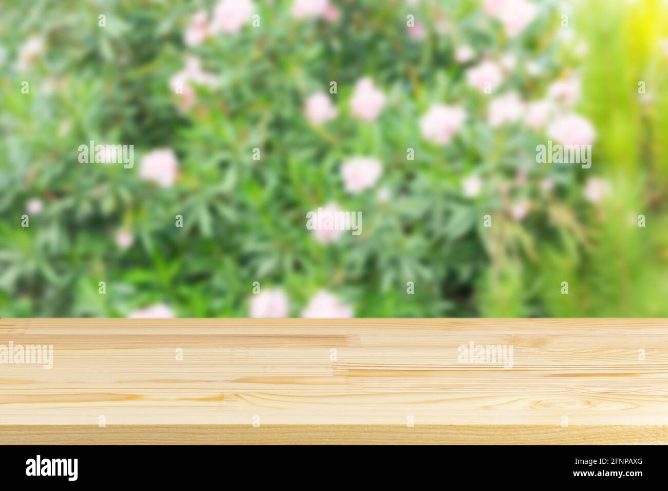 wood table top on blur bush with flowers background Stock Photo - Alamy