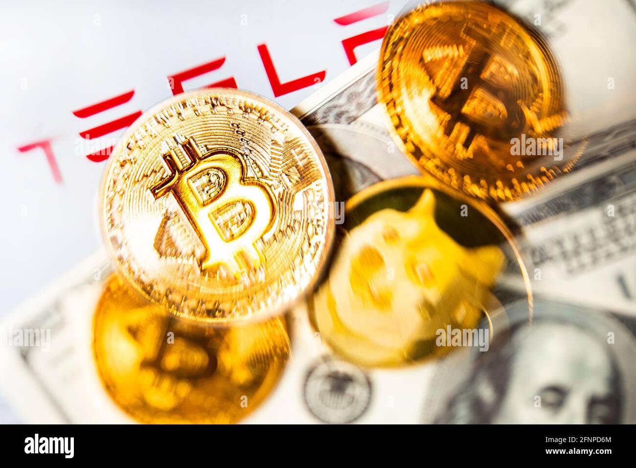 Gold coins of a cryptocurrency, US dollars and the Tesla company logo ...