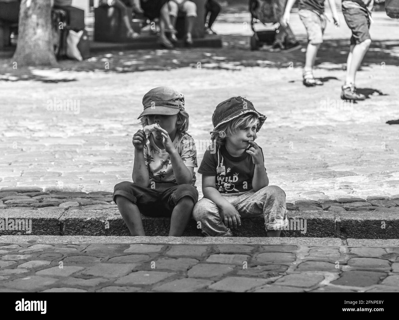 Two boys sat down watching street life Stock Photo - Alamy