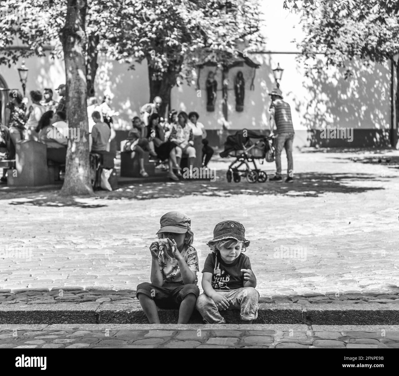 Two boys sat down watching street life Stock Photo - Alamy