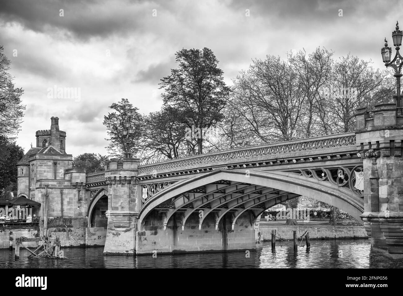 A historic stone bridge with ornate metalwork and towers span a river ...