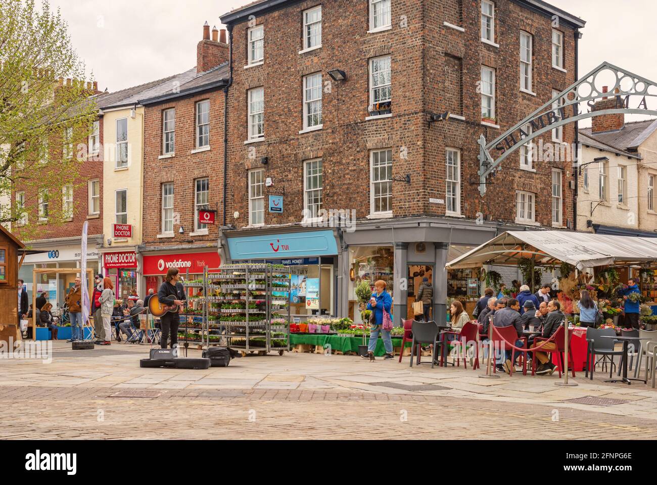 A pedestrian shopping street with people sitting outside at a cafe. A ...