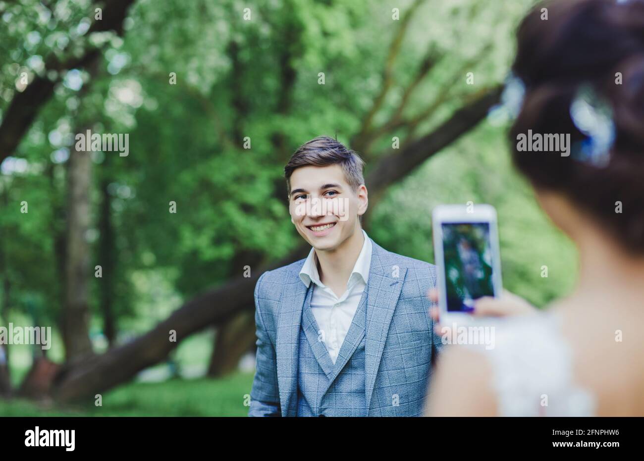 the bride takes pictures of the groom on his phone on the wedding day ...