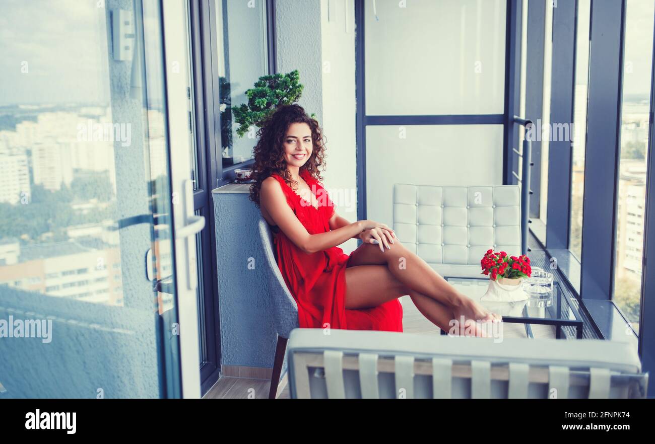 beautiful elegant woman in red dress sitting on balcony Stock Photo - Alamy