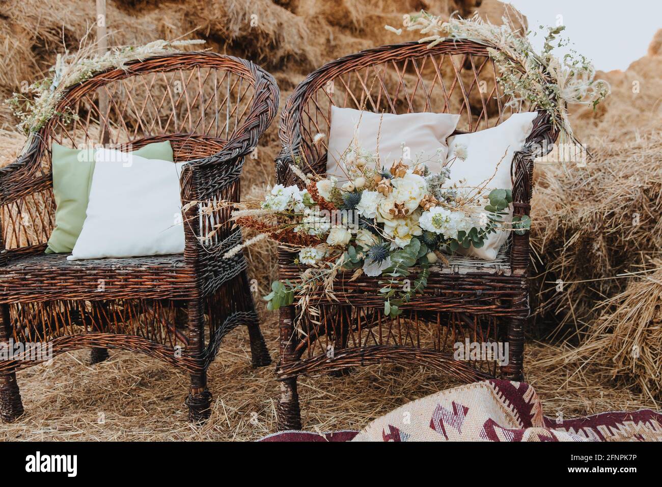 Two wicker chairs with cushions and a bouquet of flowers on it. Rattan ...