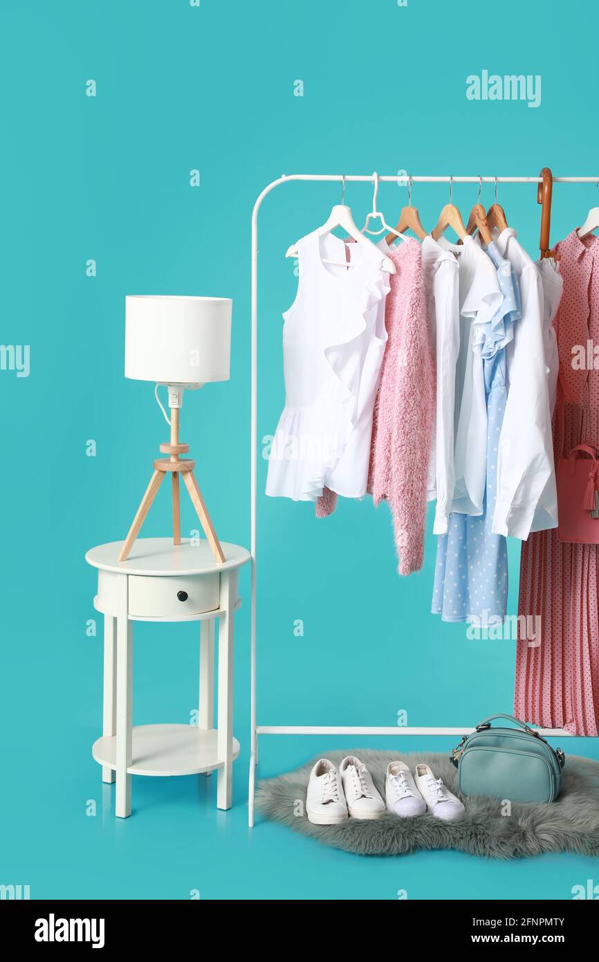 Rack with stylish clothes, accessories and table on color background ...