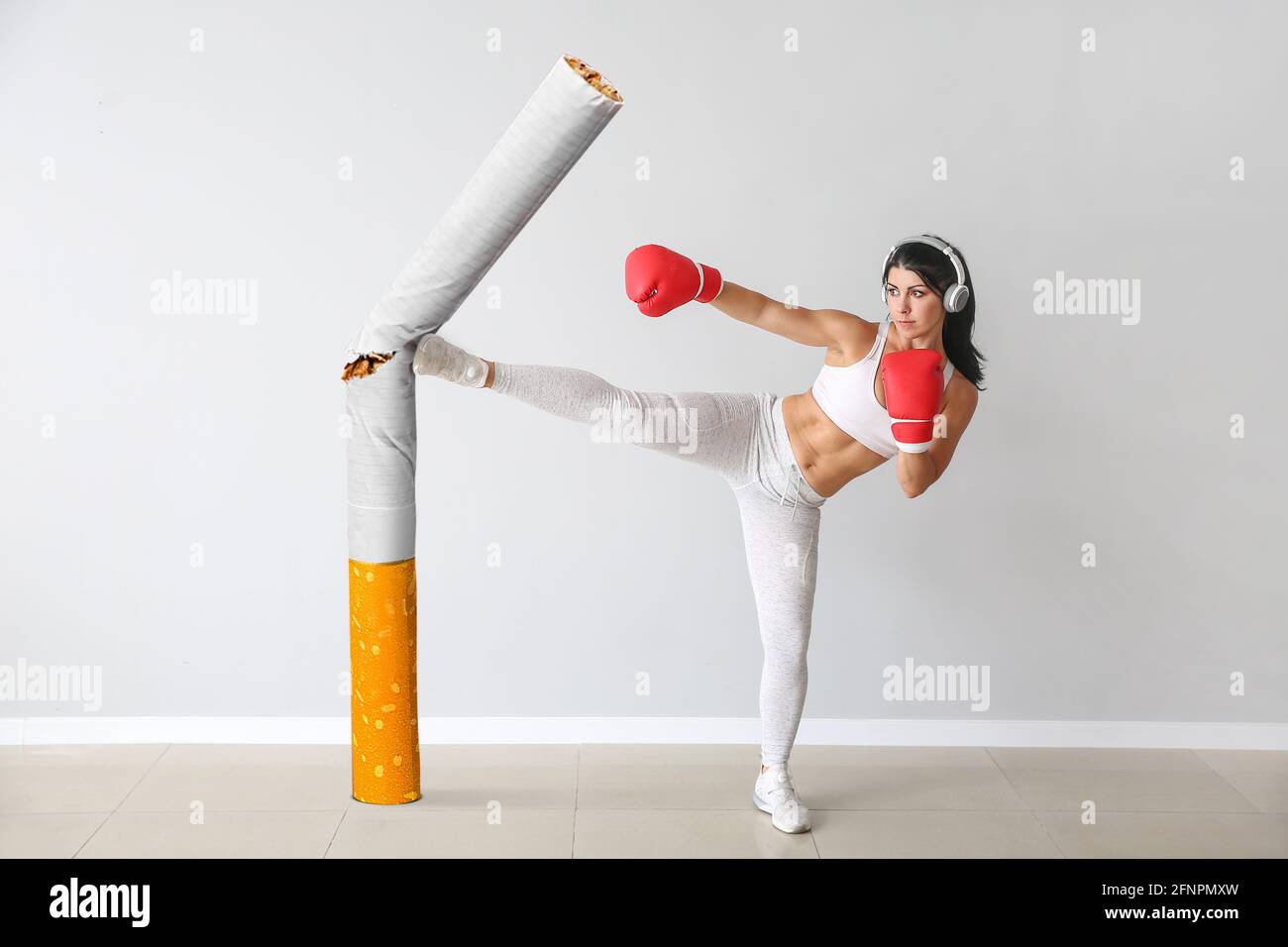 Sporty female boxer kicking cigarette near light wall Stock Photo - Alamy