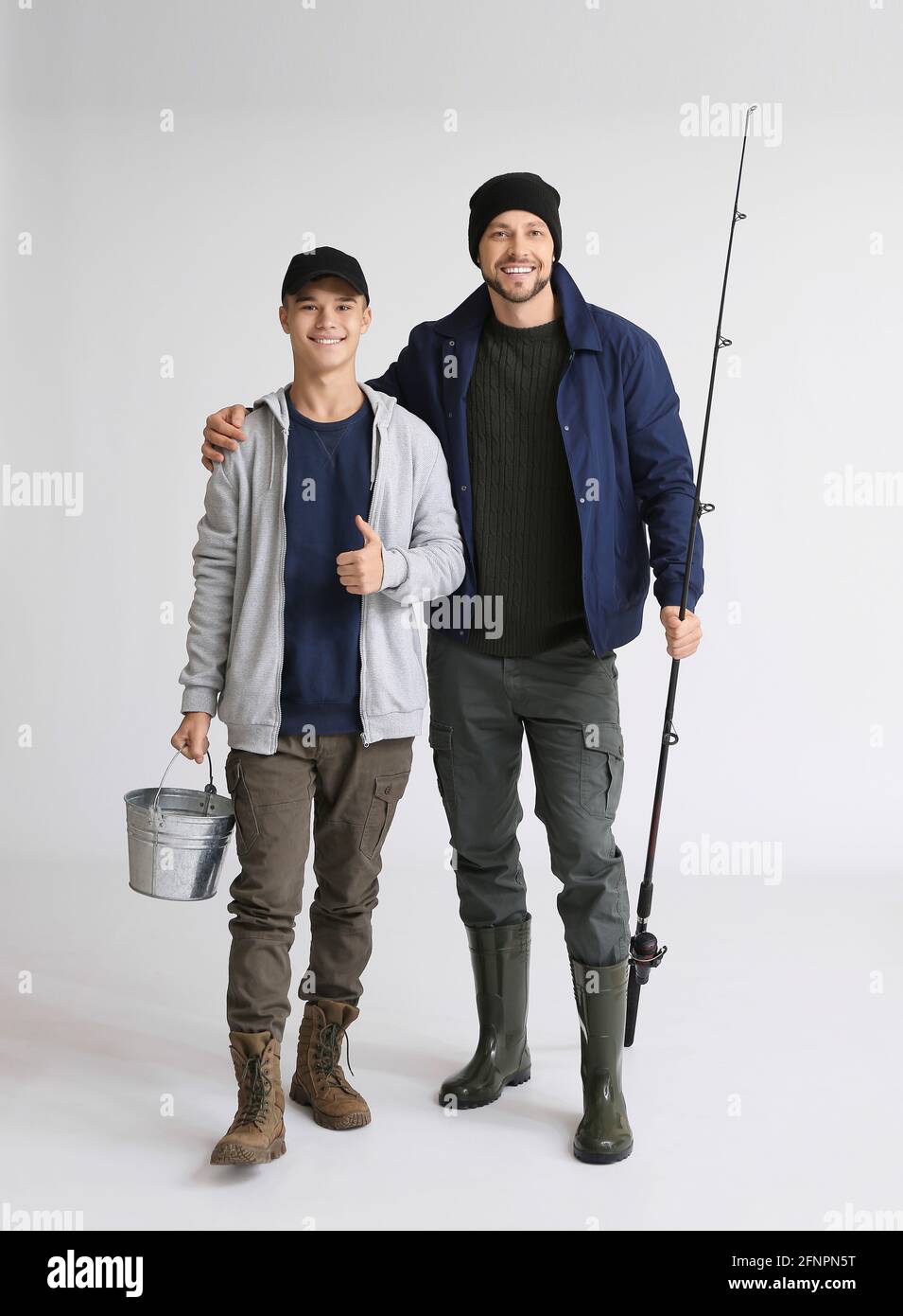 Happy father and son with fishing rod and bucket on white background ...