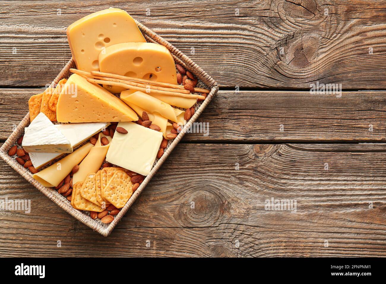 Tray with different types of cheese and snacks on wooden background ...