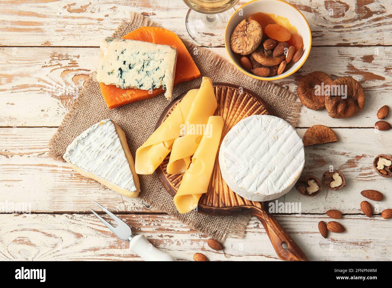 Different types of cheese, dried fruits and nuts on light wooden ...