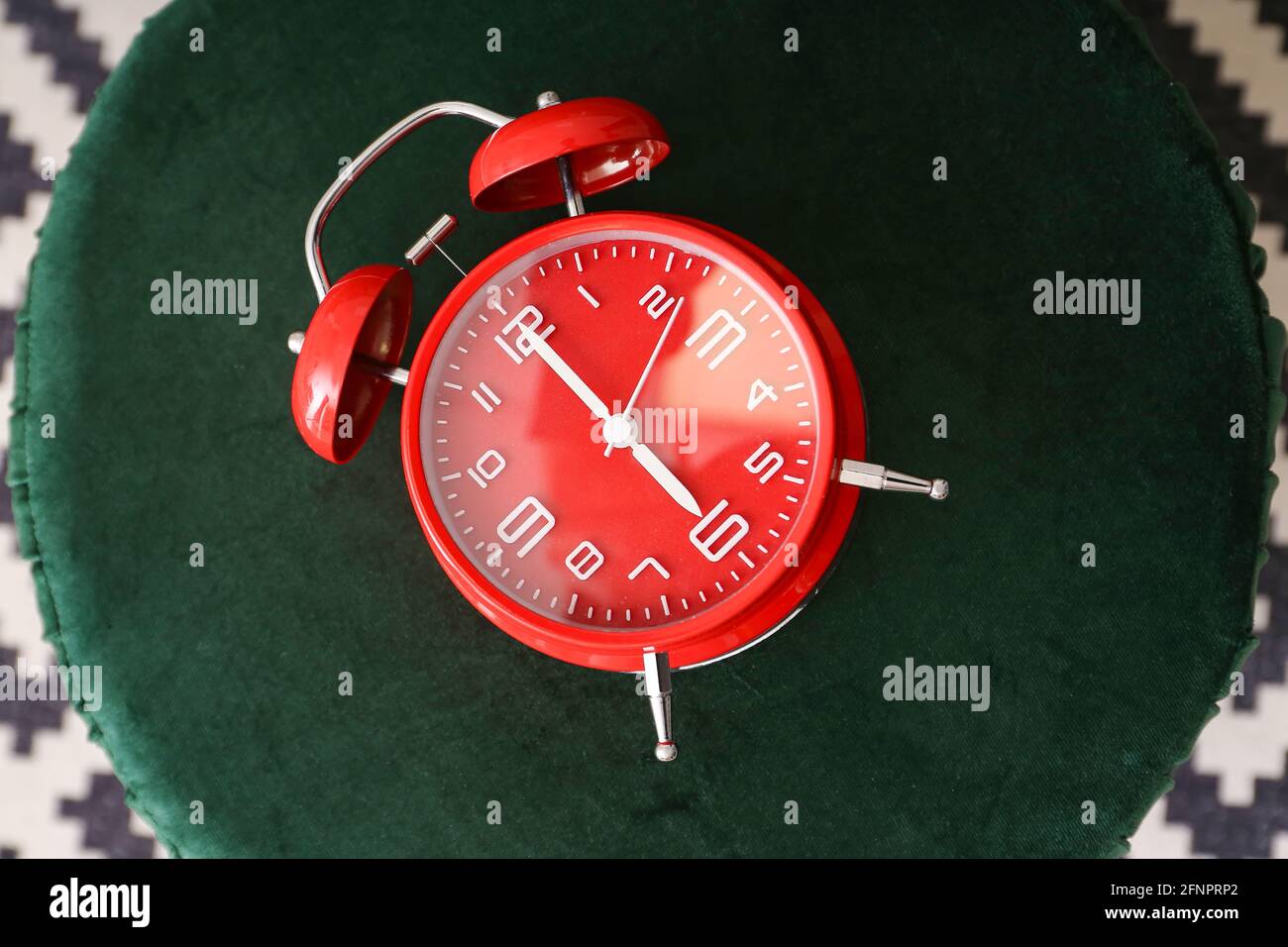 Alarm clock on ottoman in room Stock Photo - Alamy