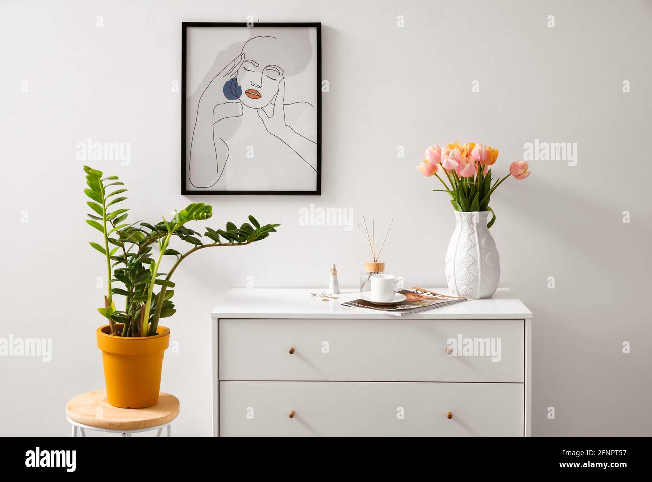 Tulip flowers on chest of drawers near white wall Stock Photo - Alamy