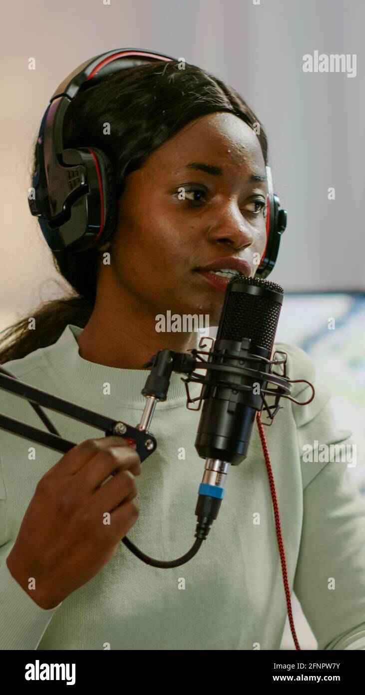 African woman host of online show talking into microphone wearing ...