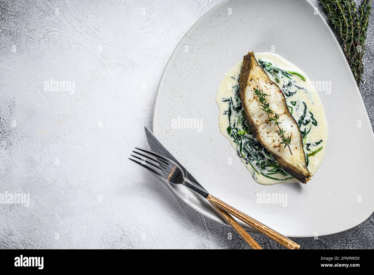 Baked Halibut fish steak with spinach. White background. Top view. Copy ...