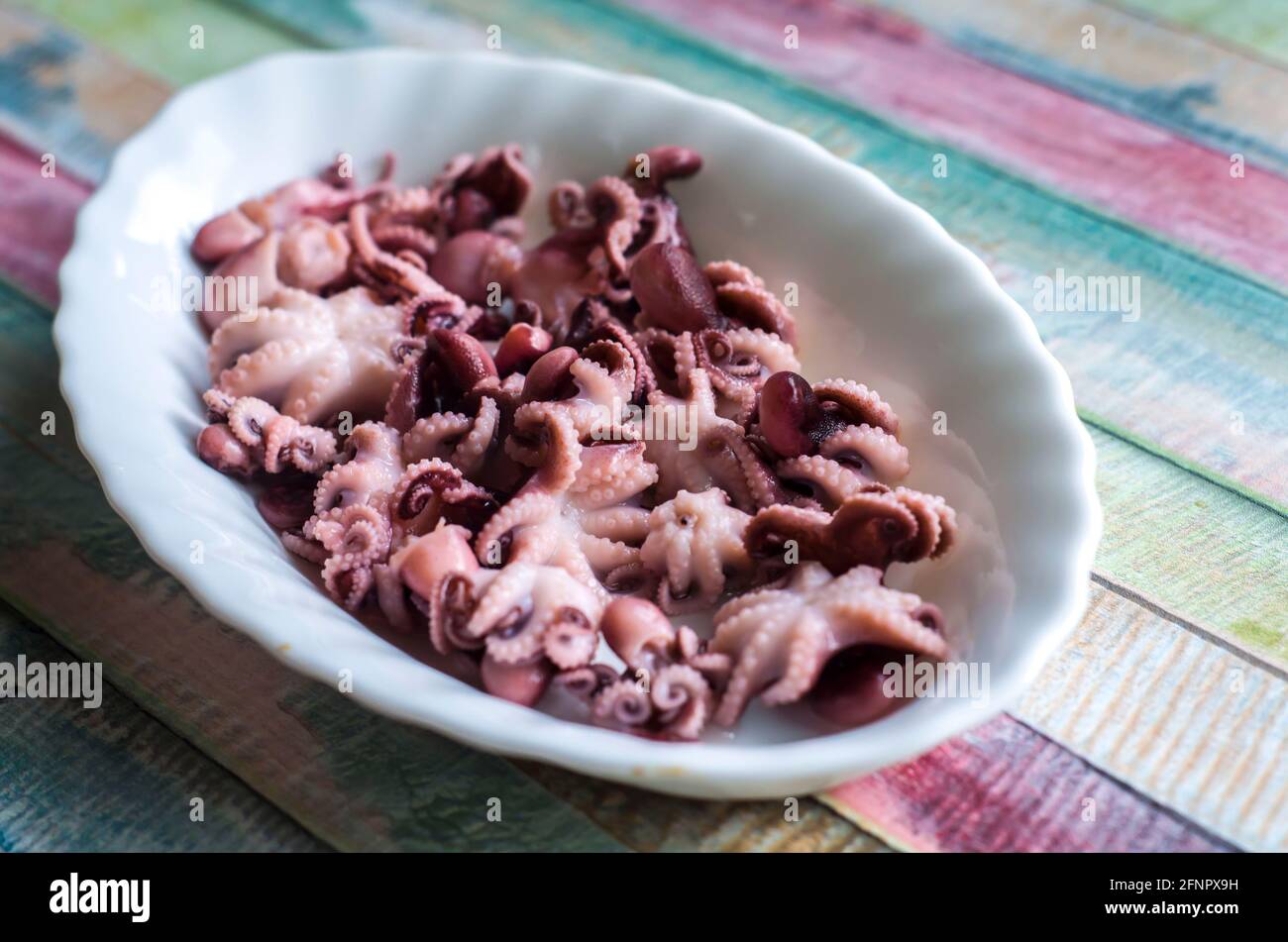 Little octopuses on a plate on a wooden colored background.Seafood ...