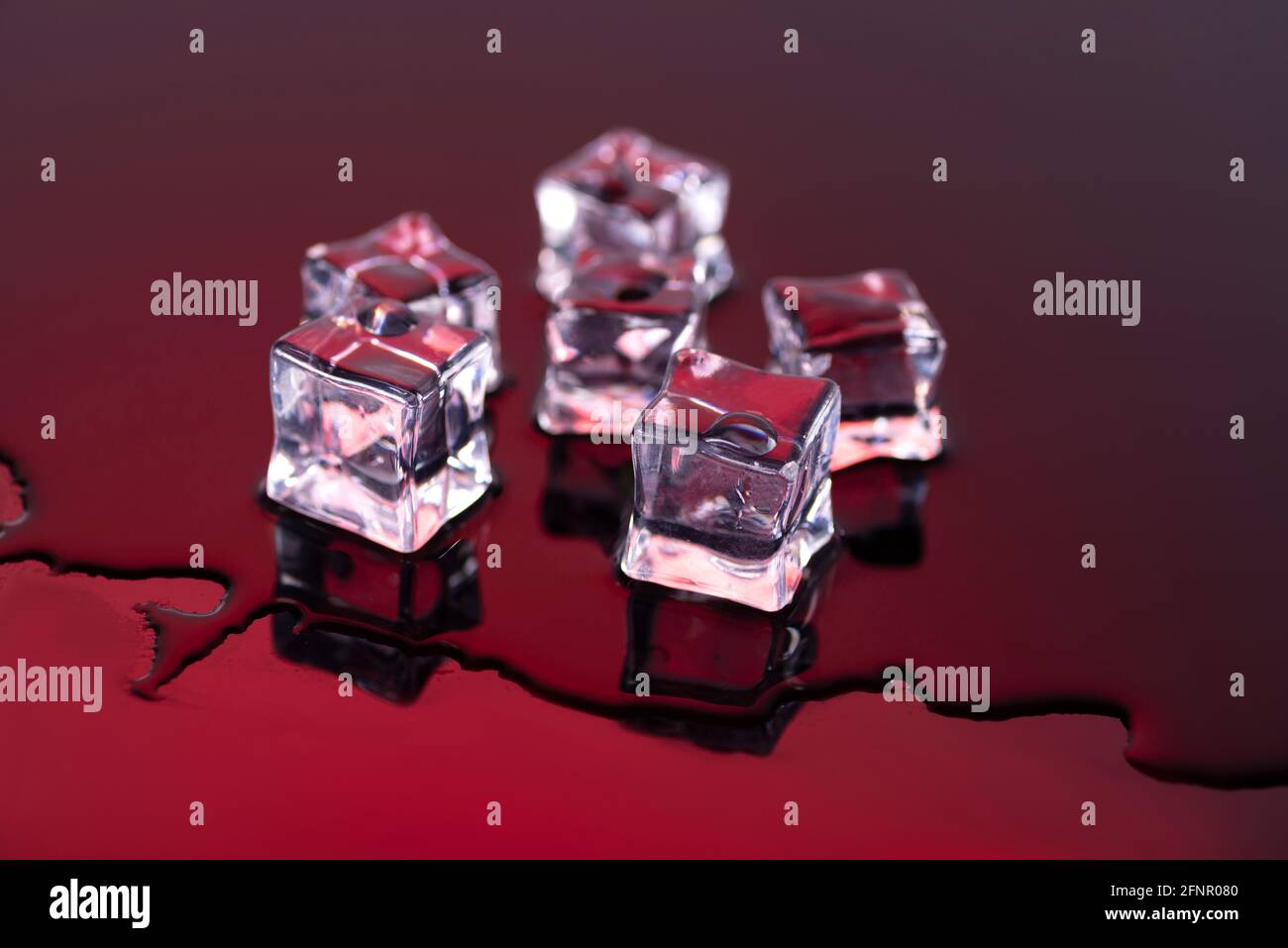 Wet ice cubes in a puddle of water on a red background Stock Photo - Alamy