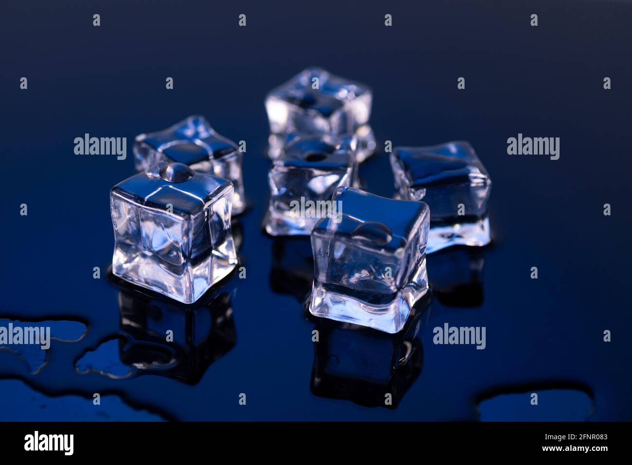 Wet ice cubes in a puddle of water on a blue background Stock Photo - Alamy