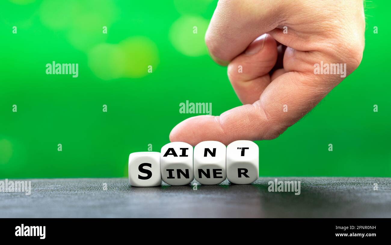 Hand turns dice and changes the word "sinner" to "saint Stock Photo - Alamy