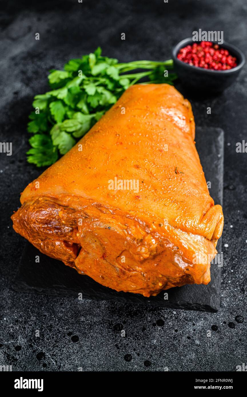 Raw pork leg with herbs and marinate on table. Black background. Top ...