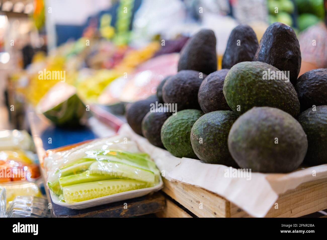 Pile of avocados and sliced cucumbers on vegetable stand Stock Photo ...