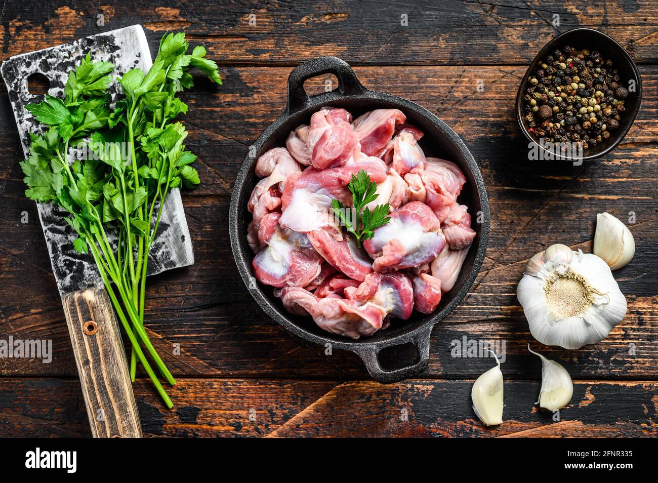 Raw uncooked Bird chicken giblets gizzards, stomachs in a pan. Black ...