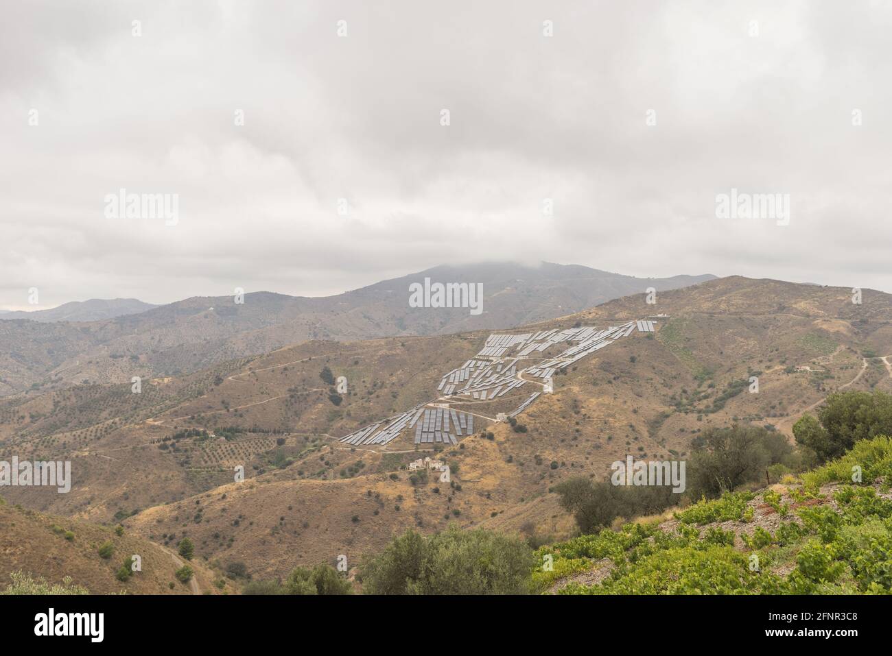 Landscape of hills covered in greenery under a cloudy sky in Axarquia ...