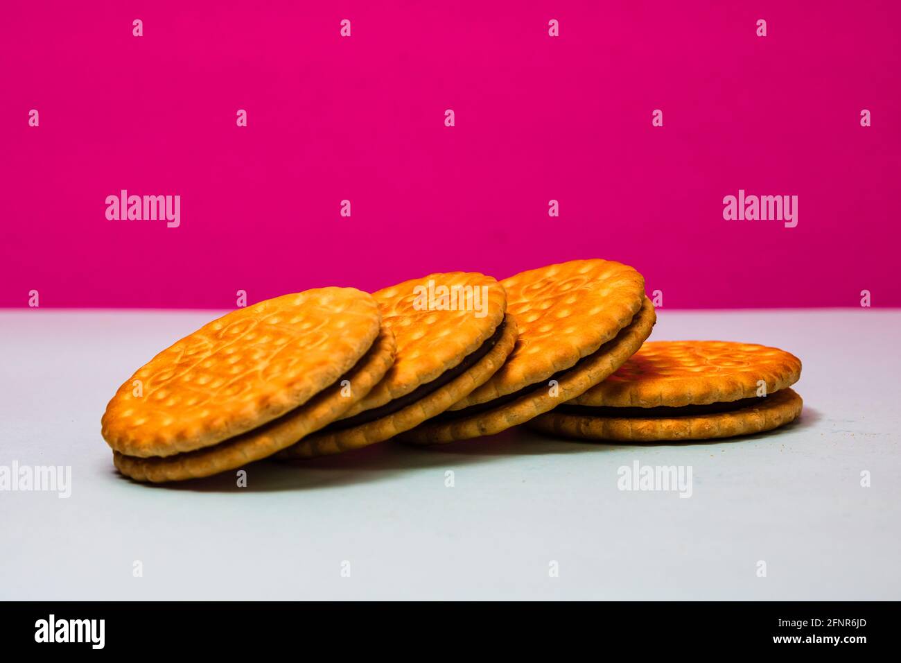 Shot of round biscuits with chocolate cream isolated on pink background ...