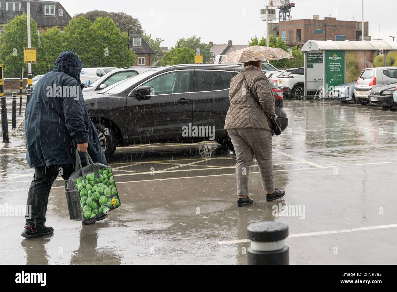 shoppers caught inthe rain outside Morrisons supermarket, London ...