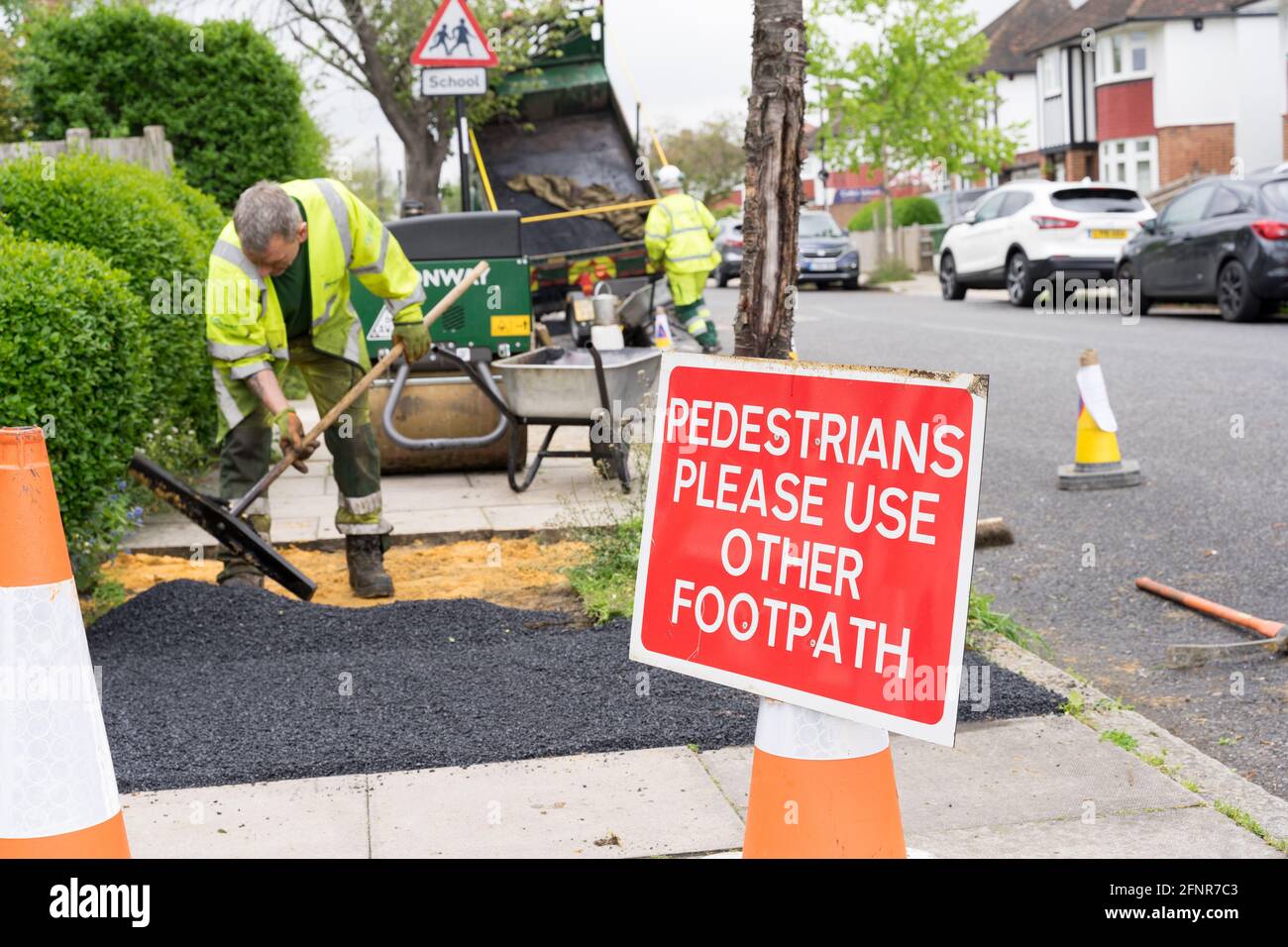 Engineer lays new tarmac to build new pavement, footpath, London ...