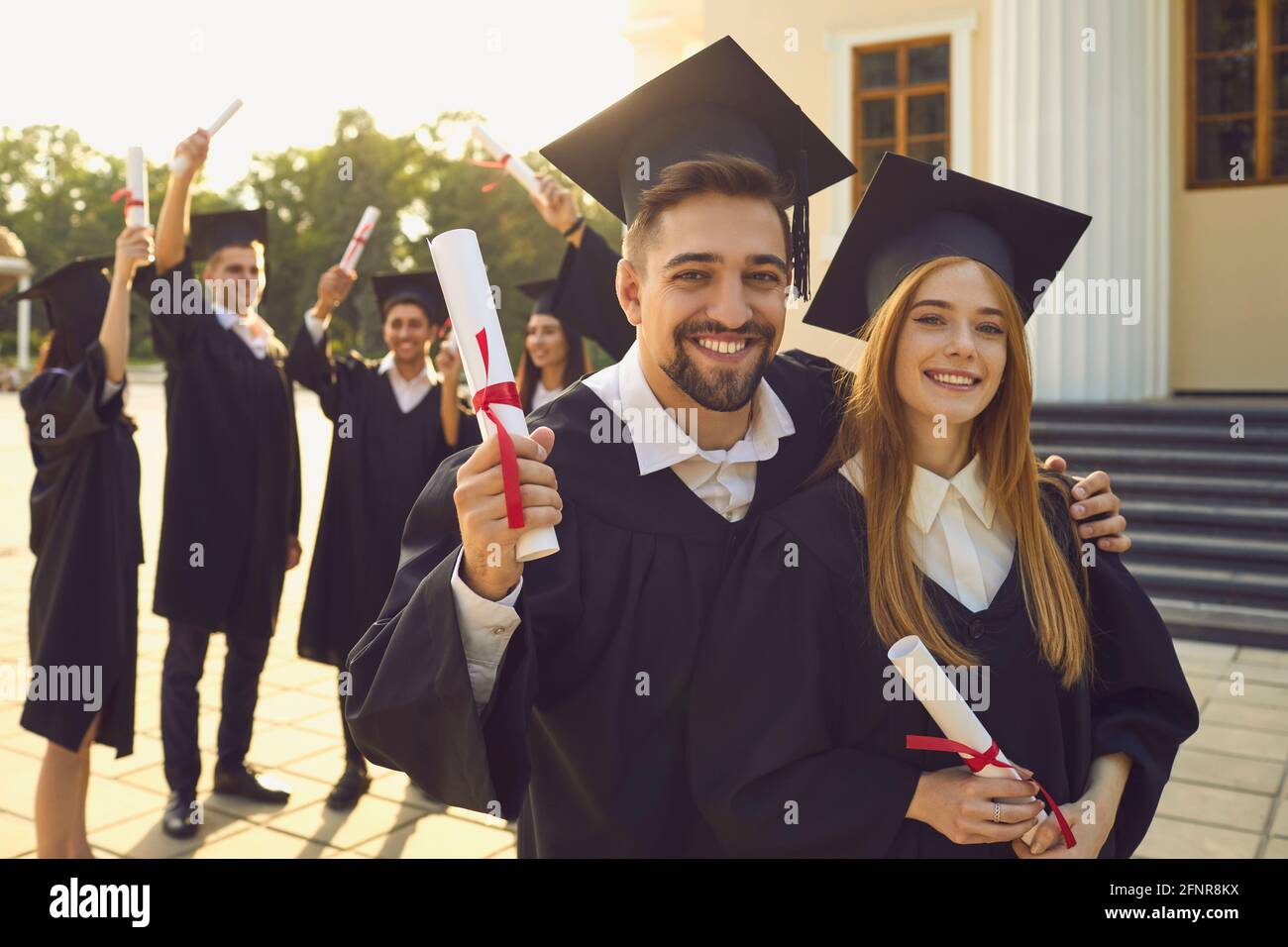 Happy graduates with degree certificates looking at camera Stock Photo ...