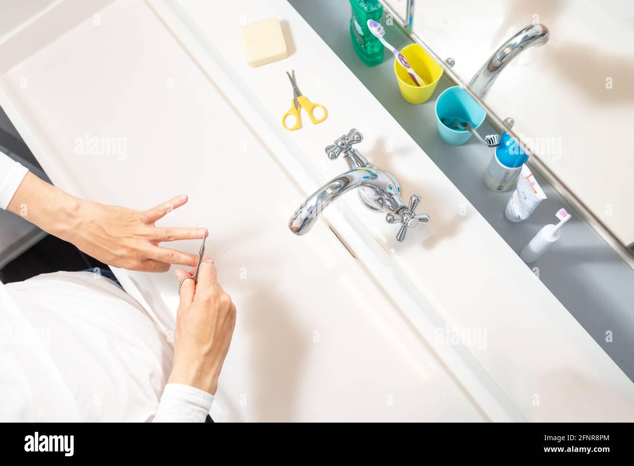 homemade manicure in the bathroom, hands with nail scissors in bathroom ...