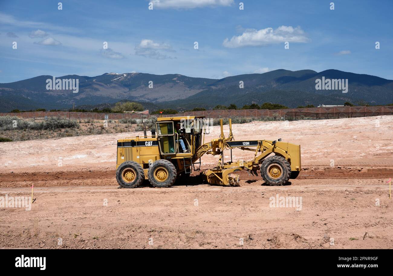 A heavy-equipment operator uses a Caterpillar 120H motor grader to move ...