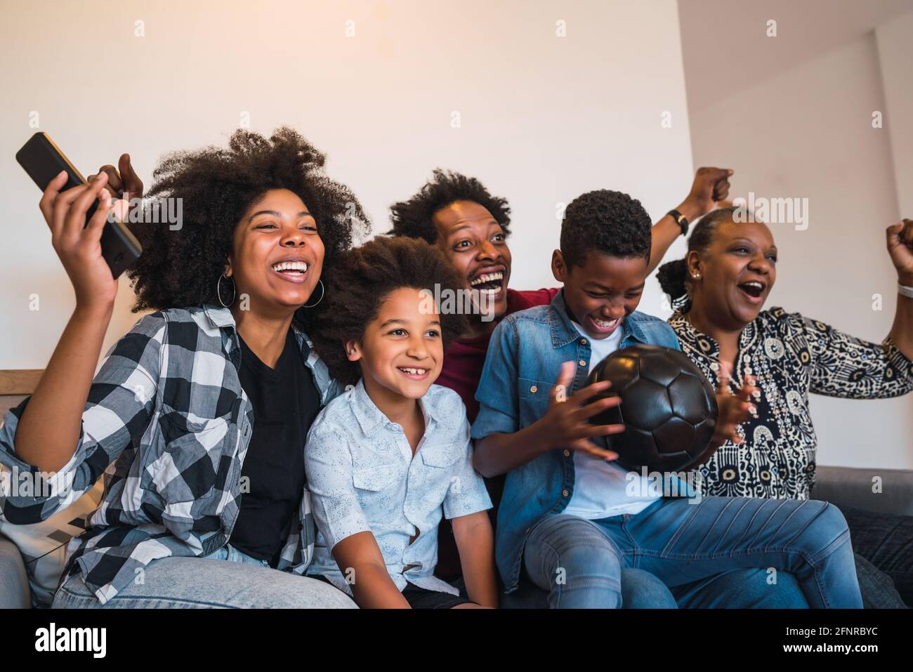 Multi-generation family watching soccer match at home Stock Photo - Alamy