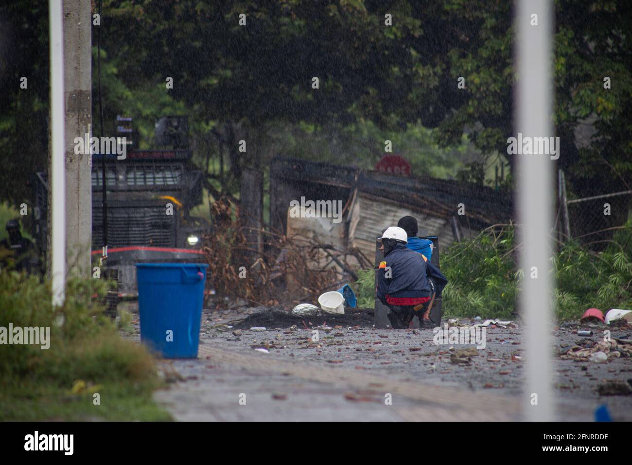 Demonstrators take cover behind a homemade shield in front of a riot ...