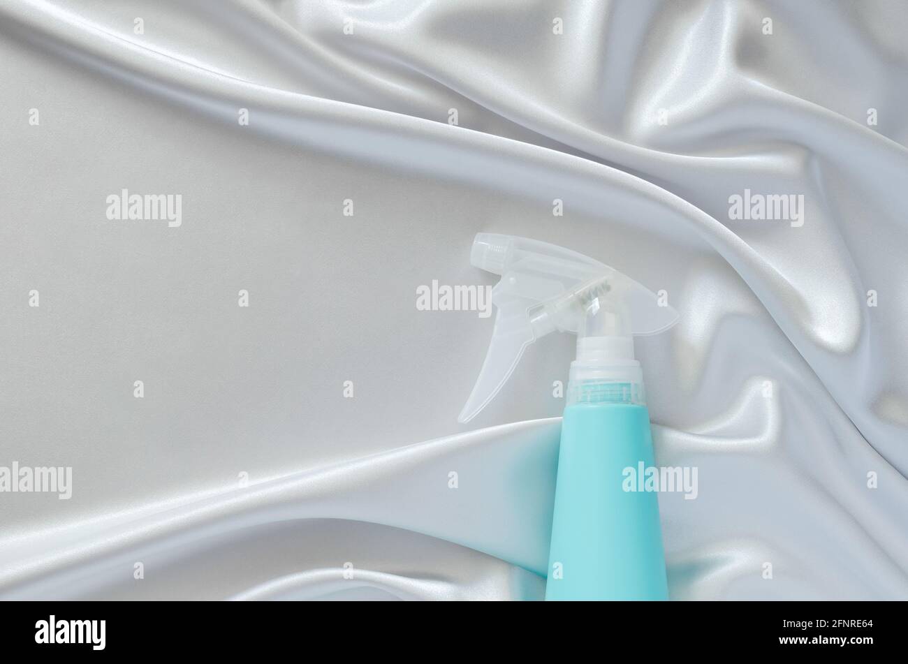 Water spray bottle on smooth and wavy grey cloth texture with space for ...