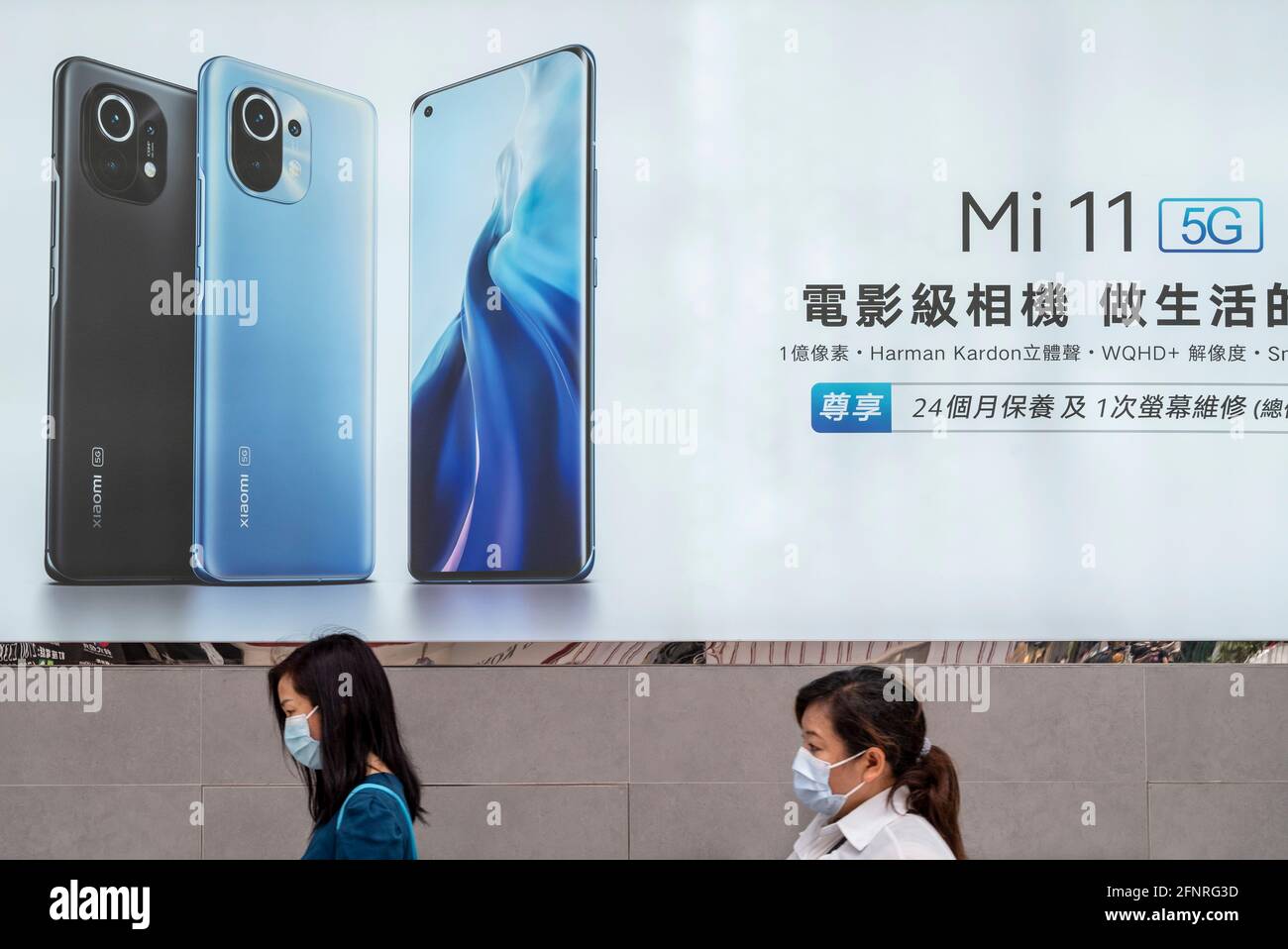 Pedestrians walk past the Xiaomi Mi 11 5G smartphone advertisement at ...
