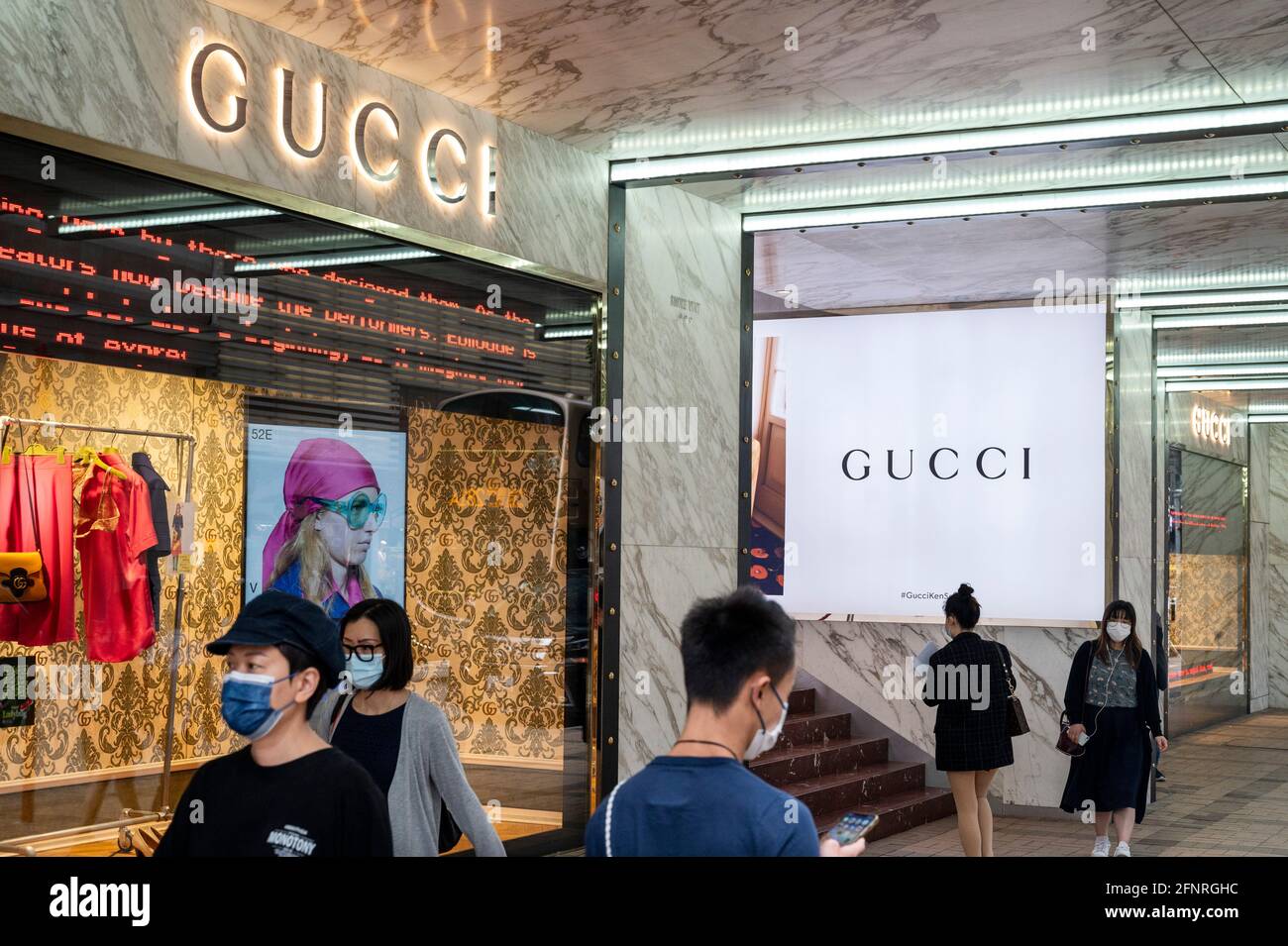 Pedestrians walk past the IItalian luxury fashion brand Gucci logo and ...