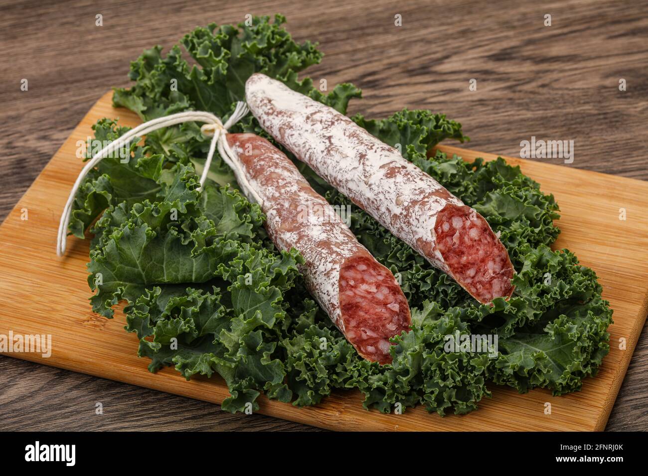 Spanish Fuet sausage with salad leaves over wooden background Stock ...